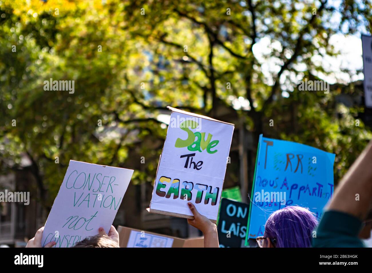 A close up view of a save the earth poster held by a climate change ...