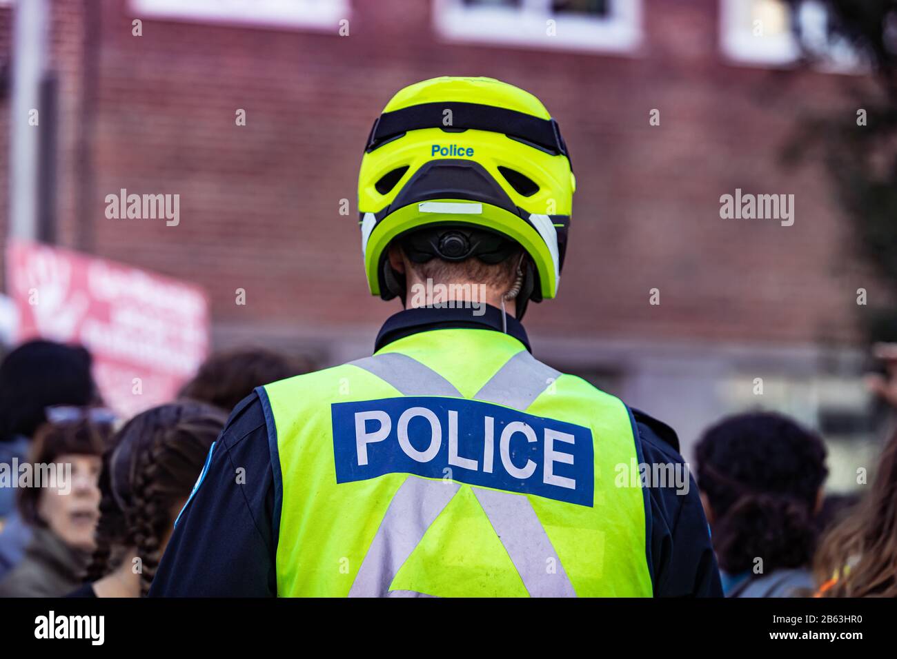 A cyclist police officer is seen from the rear, wearing high visibility ...