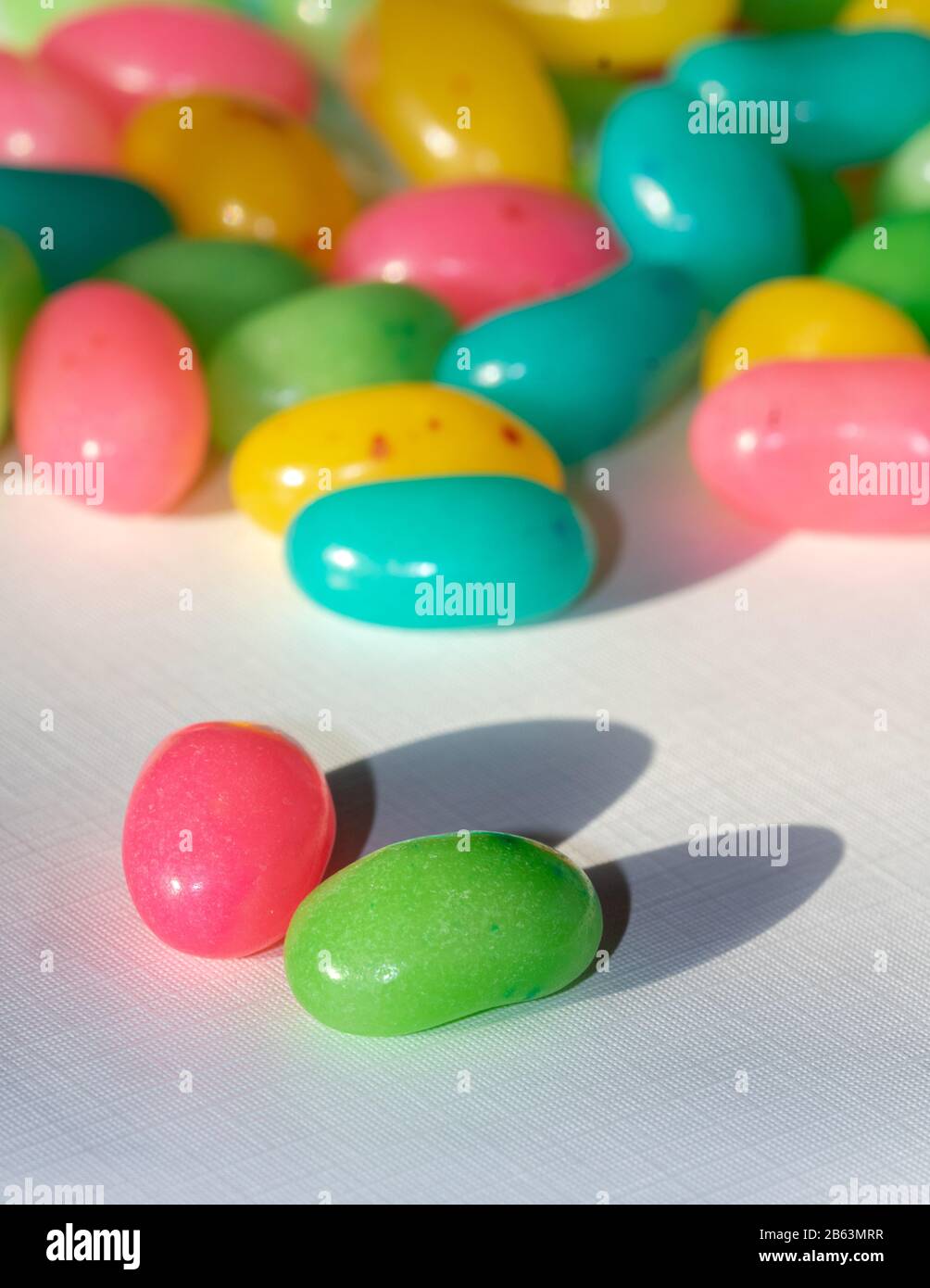 Two jelly beans lie on a surface separated from the colourful pile ...