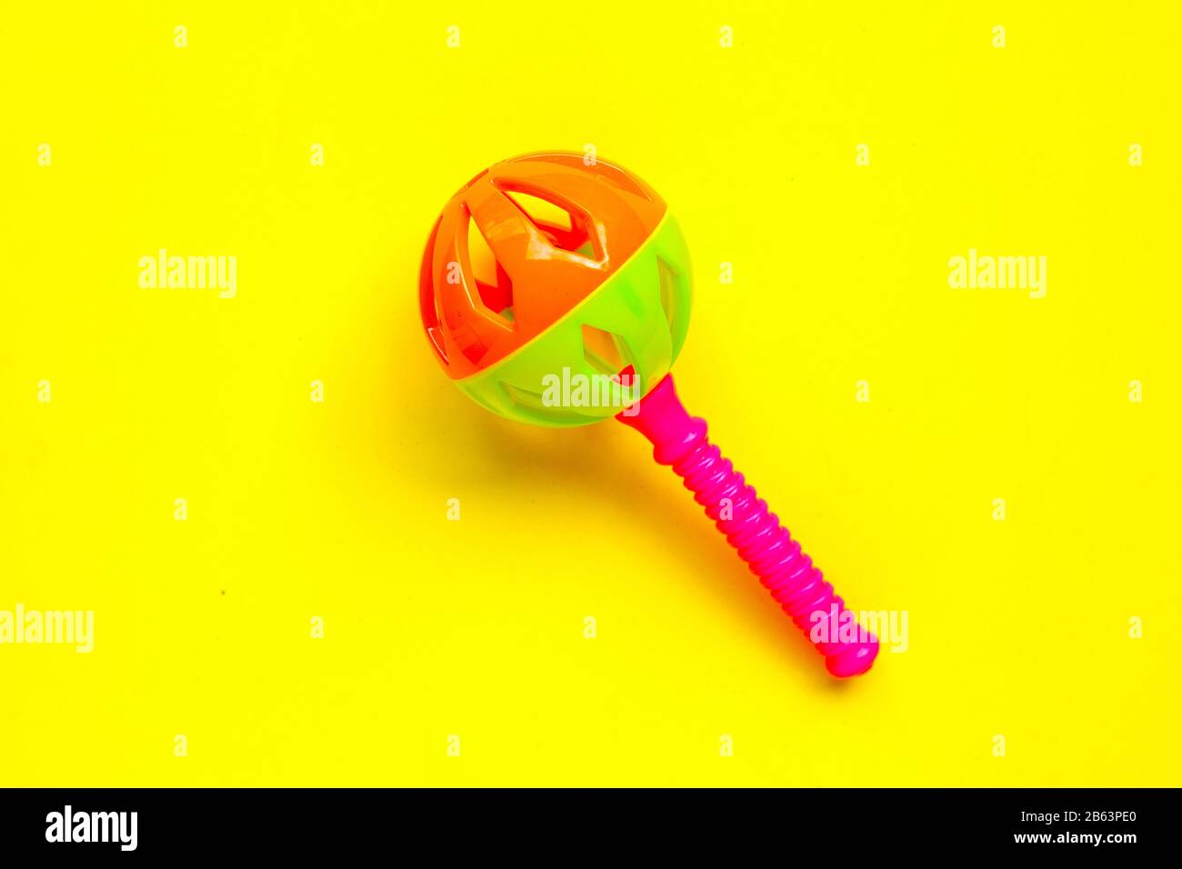 Colorful baby rattle on yellow background Stock Photo - Alamy