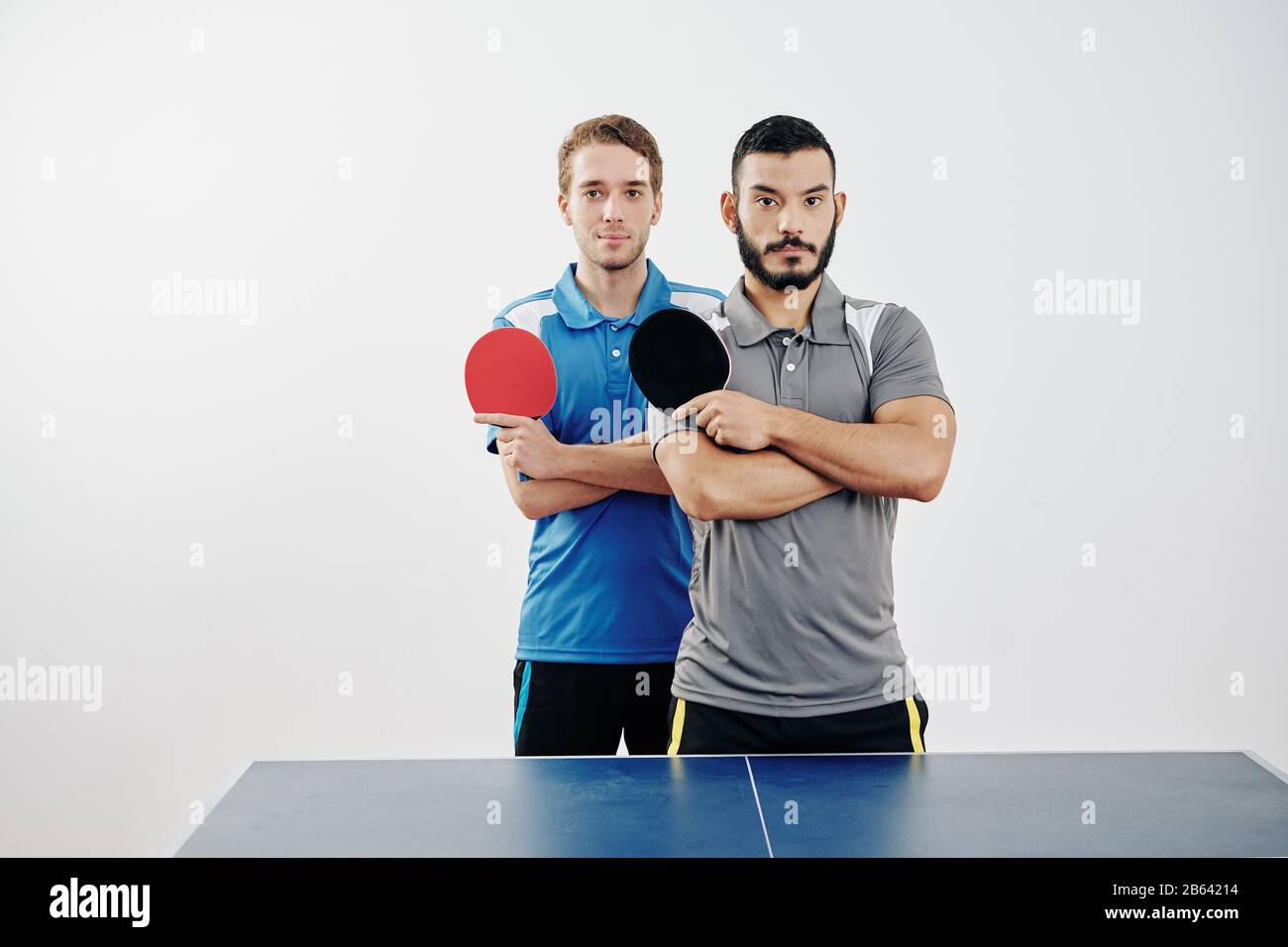 Portrait of multi-ethnic team of table tennis players in uniform posing ...