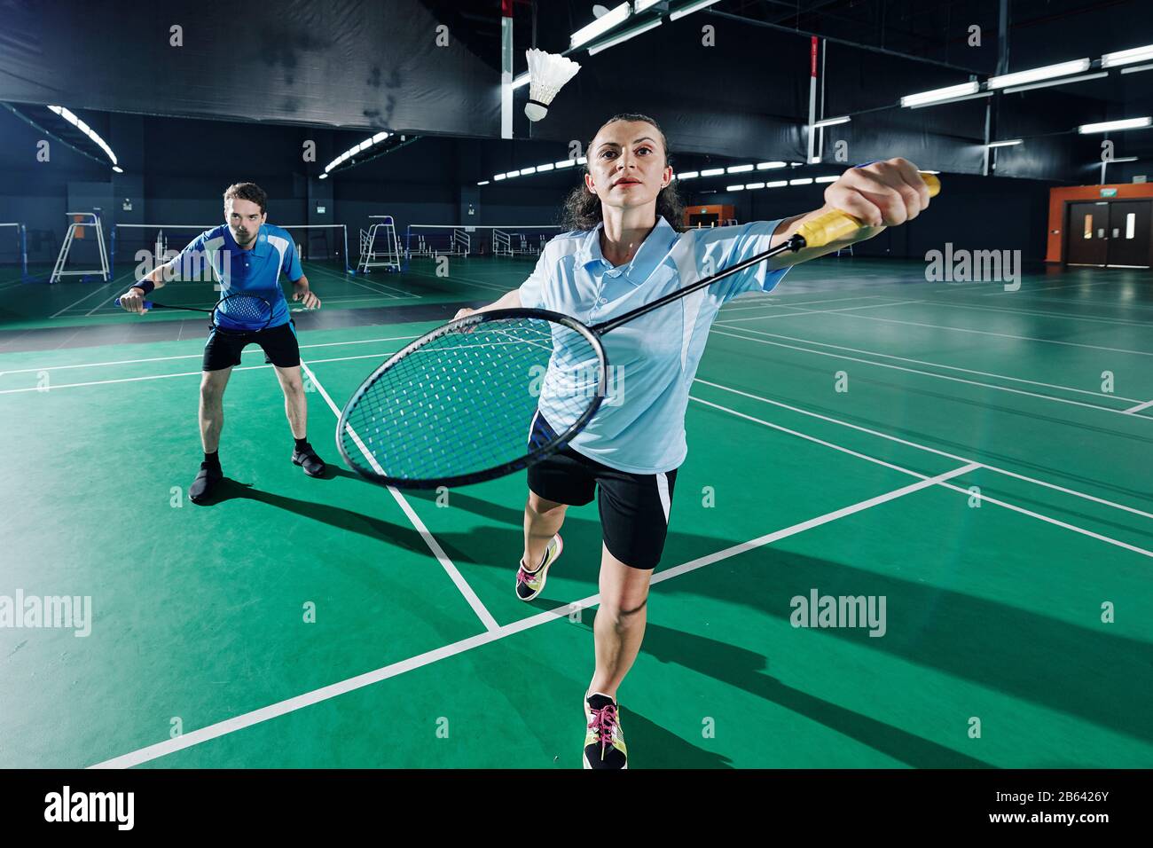 Concentrated couple playing badminton in team in gymnasium Stock Photo ...
