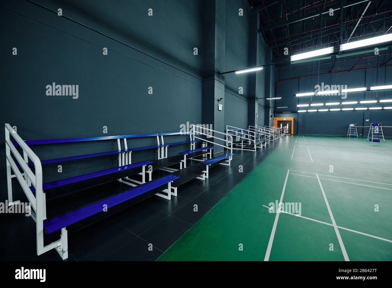 Empty benches for fans and sportsmen in gymnasium with tennis courts ...