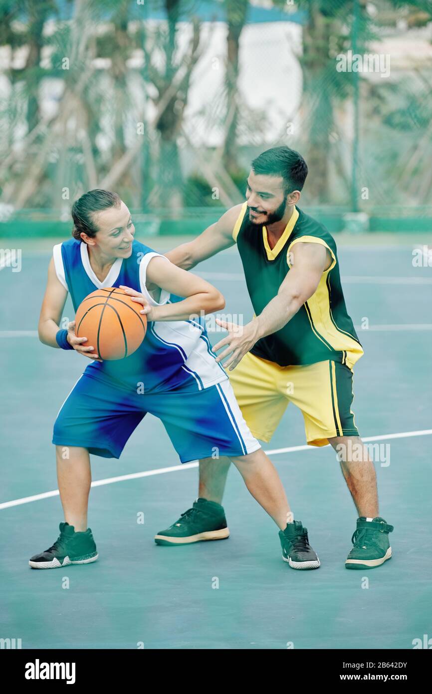 Cheerful friends playing basketball on university playground Stock ...