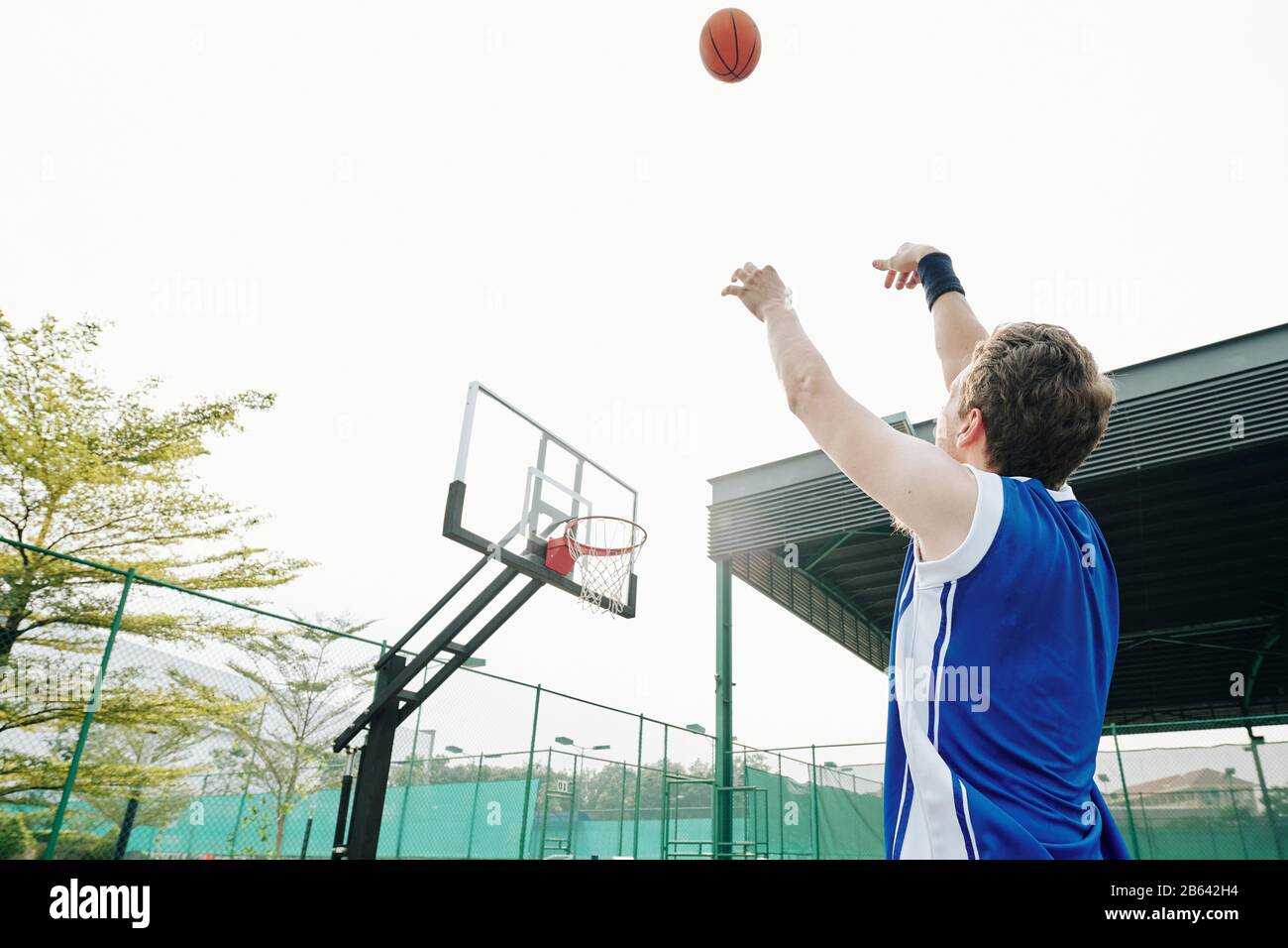 Sportsman throwing basketball ball in basket when playing outdoors ...