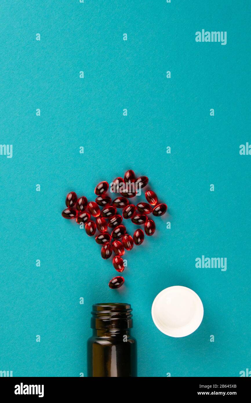 Red tablets are poured from a white plastic jar. Photo on blue ...