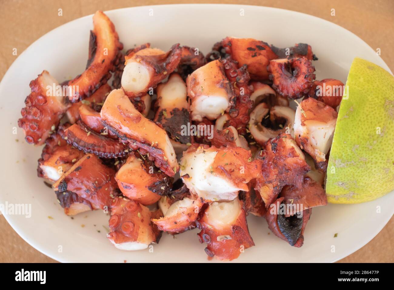 Cooked boiled and grilled octupus greek style on a white plate Stock ...