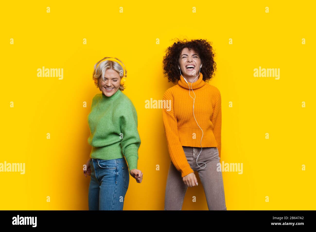 Two caucasian sisters with curly hair are having joy and dancing on a ...