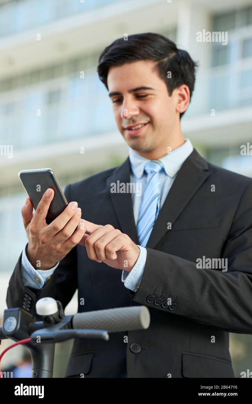 Attractive smiling young entrepreneur sending text message to coworker ...