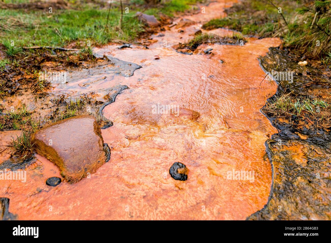 Red polluted water stream among grass Stock Photo - Alamy
