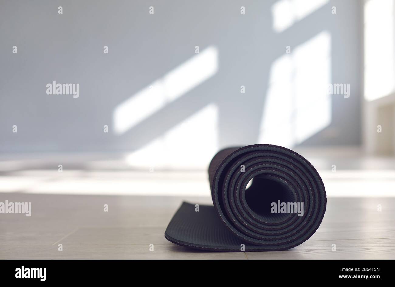 Black yoga mat on the floor of a bright sunny studio Stock Photo - Alamy
