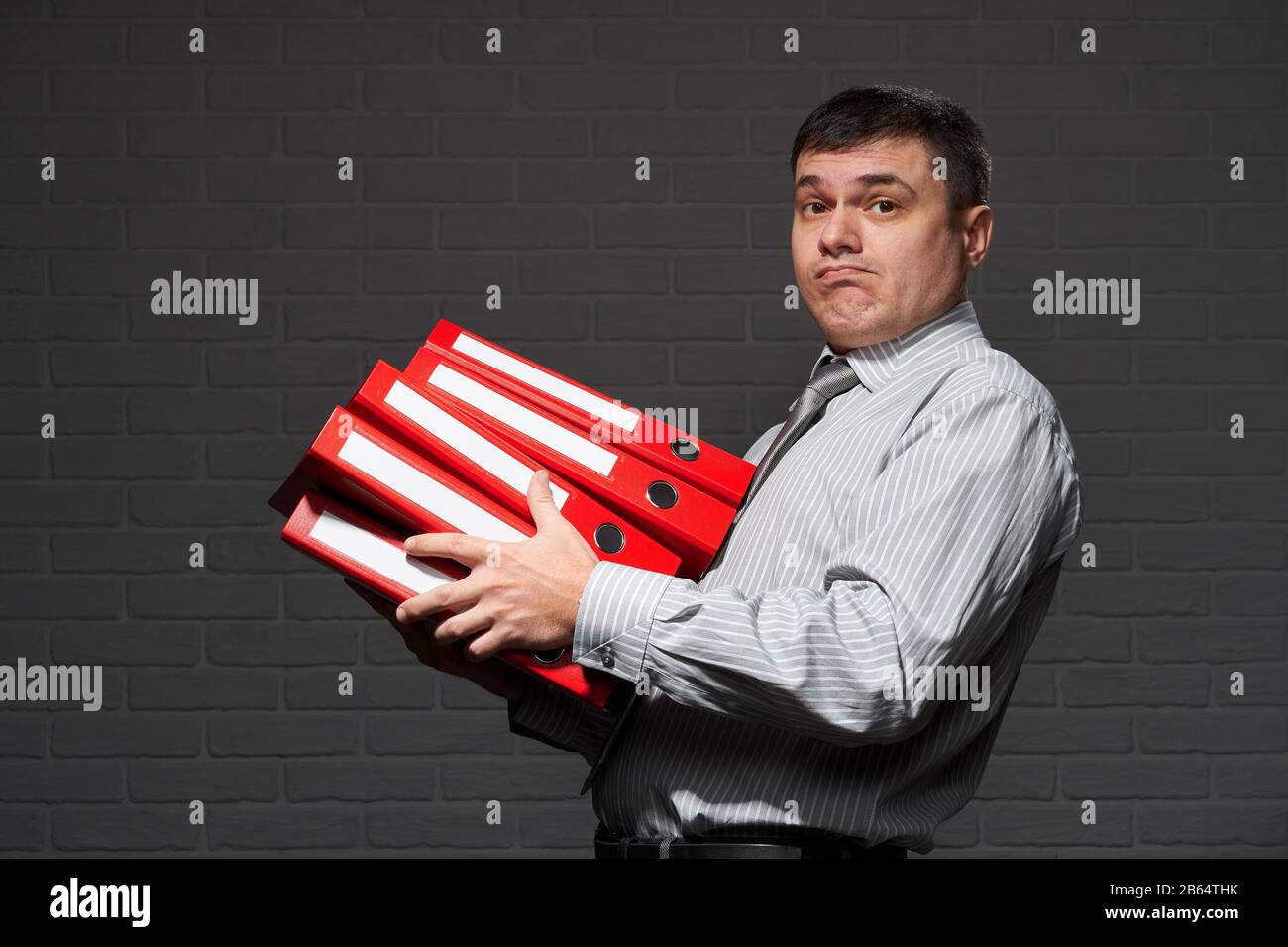 Very busy businessman closeup portrait, posing with red folders ...