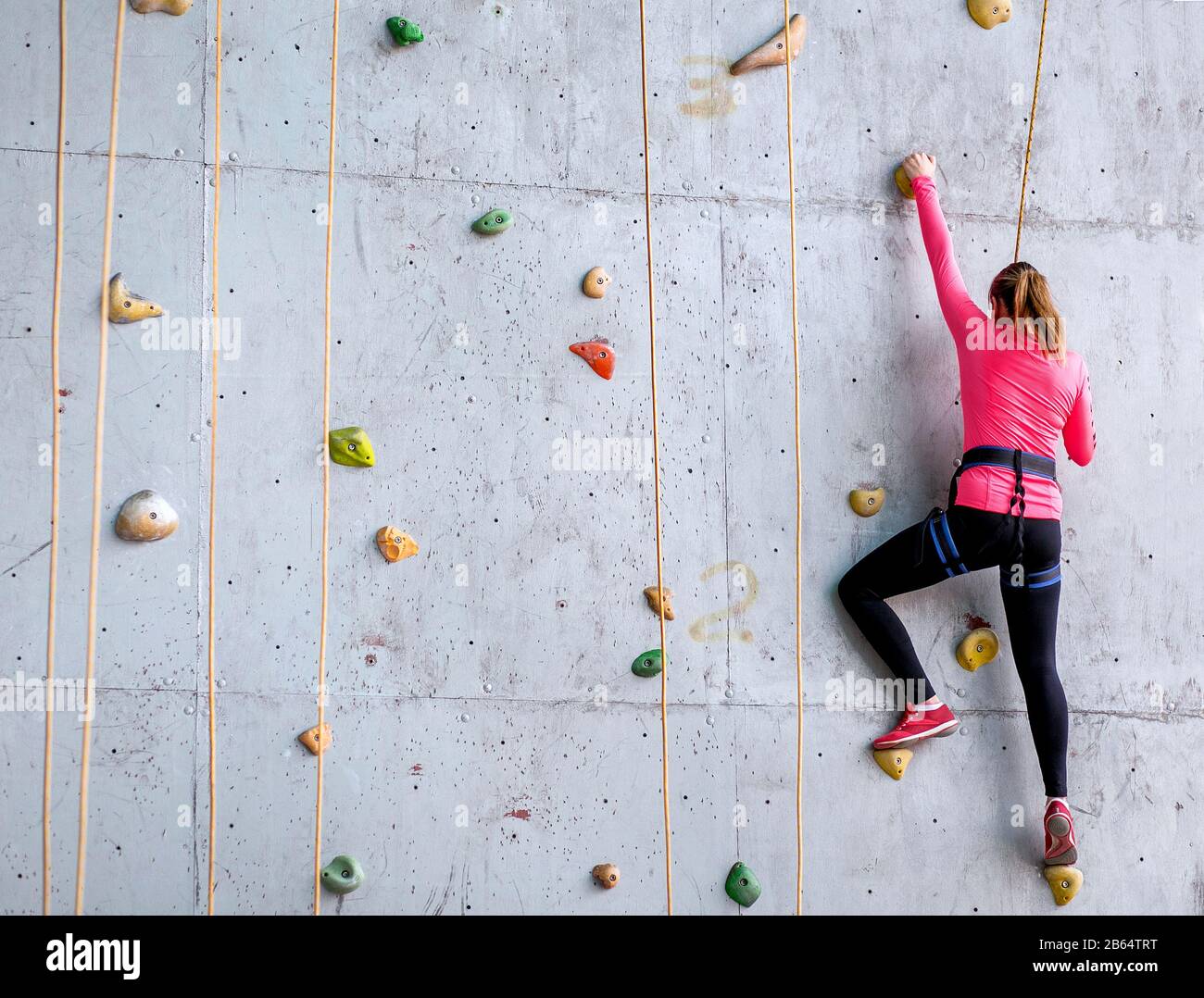 Beautiful young woman starts to climbing big artificial wall Stock ...