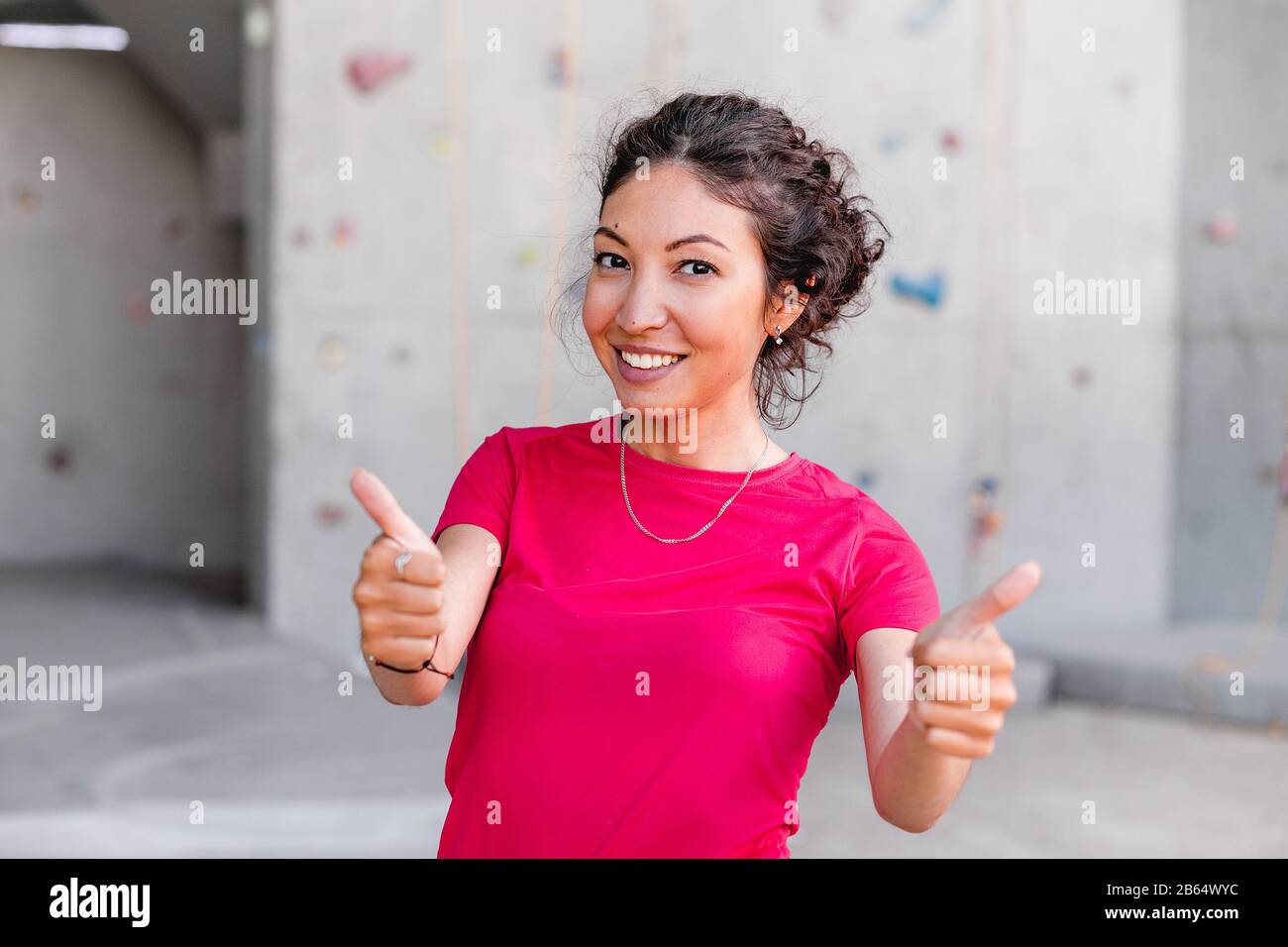 Happy smiling beautiful young woman showing thumbs up gesture, climbing ...