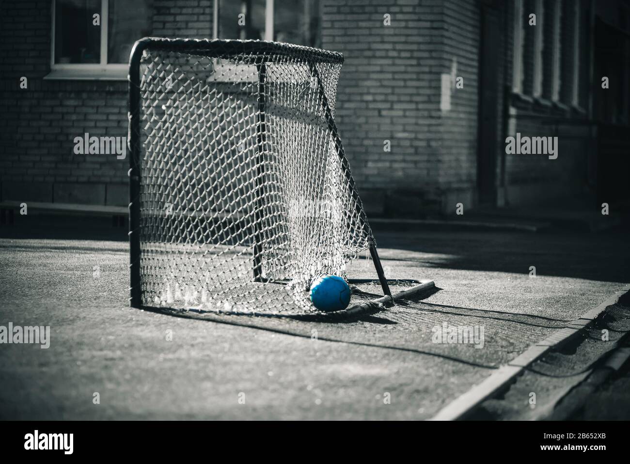 Soccer small gates with a torn net, in which lies a scored blue soccer ...