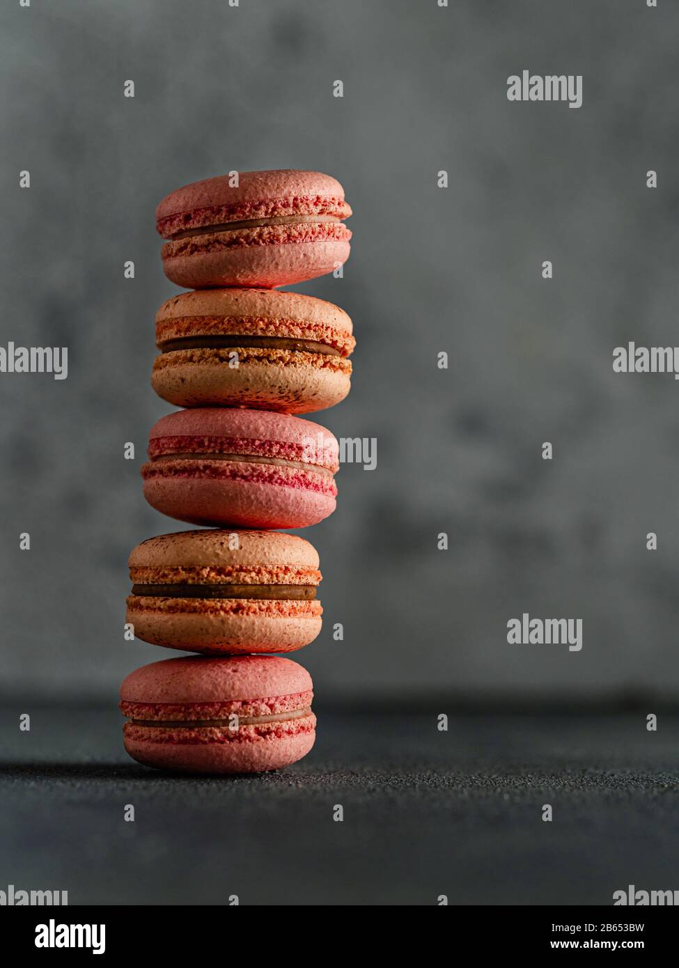 Stack of perfect french macarons. Vertical row of peach and pink ...