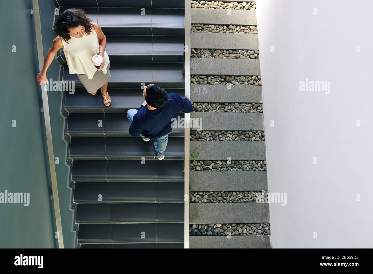 Business people standing on steps in modern office building and ...