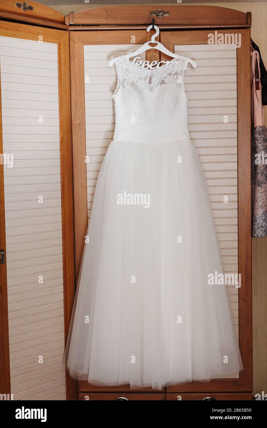 Wedding dress for the bride hanging on the rack Stock Photo - Alamy