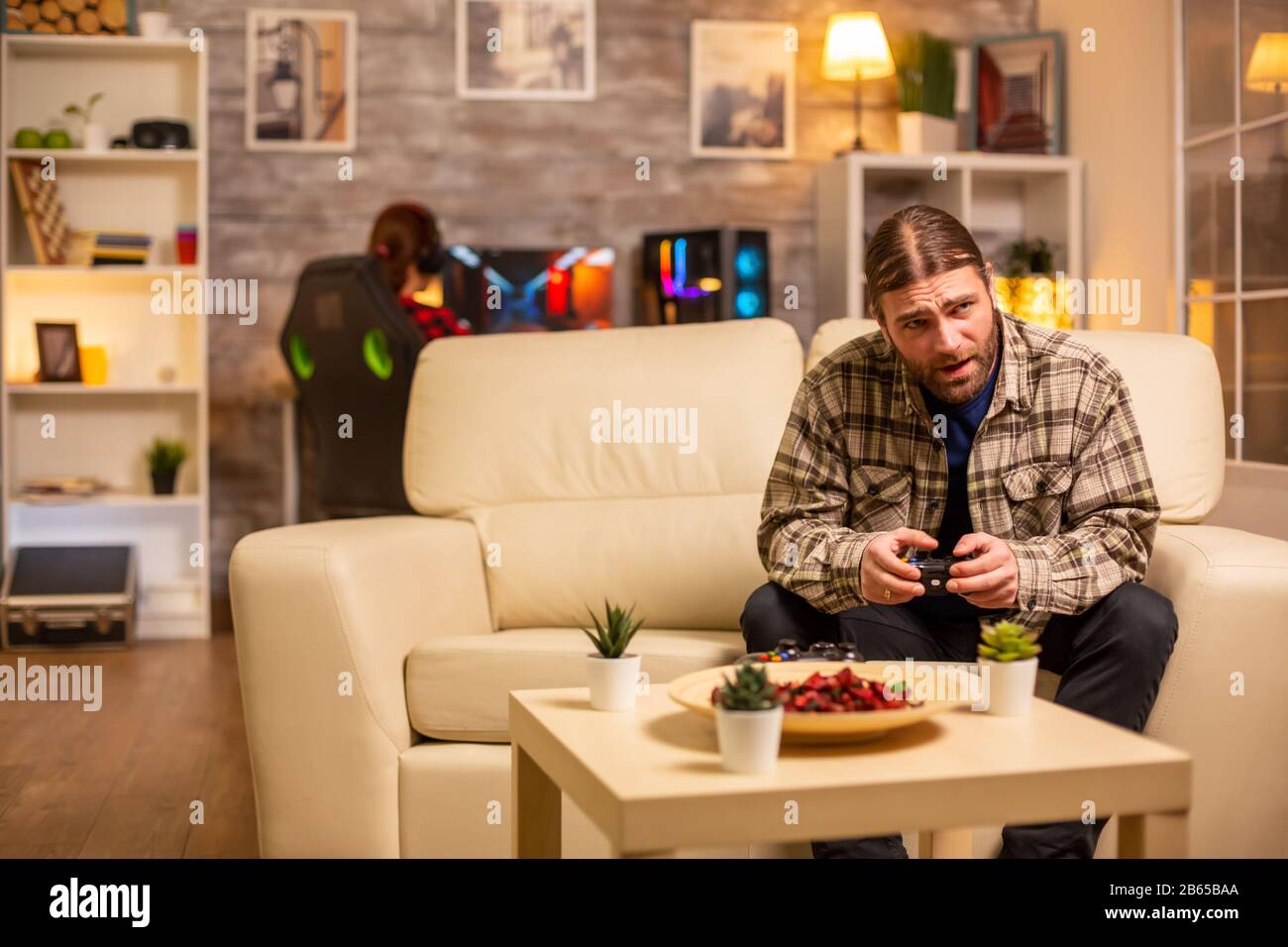 Male gamer playing video games on a console in the living room while ...