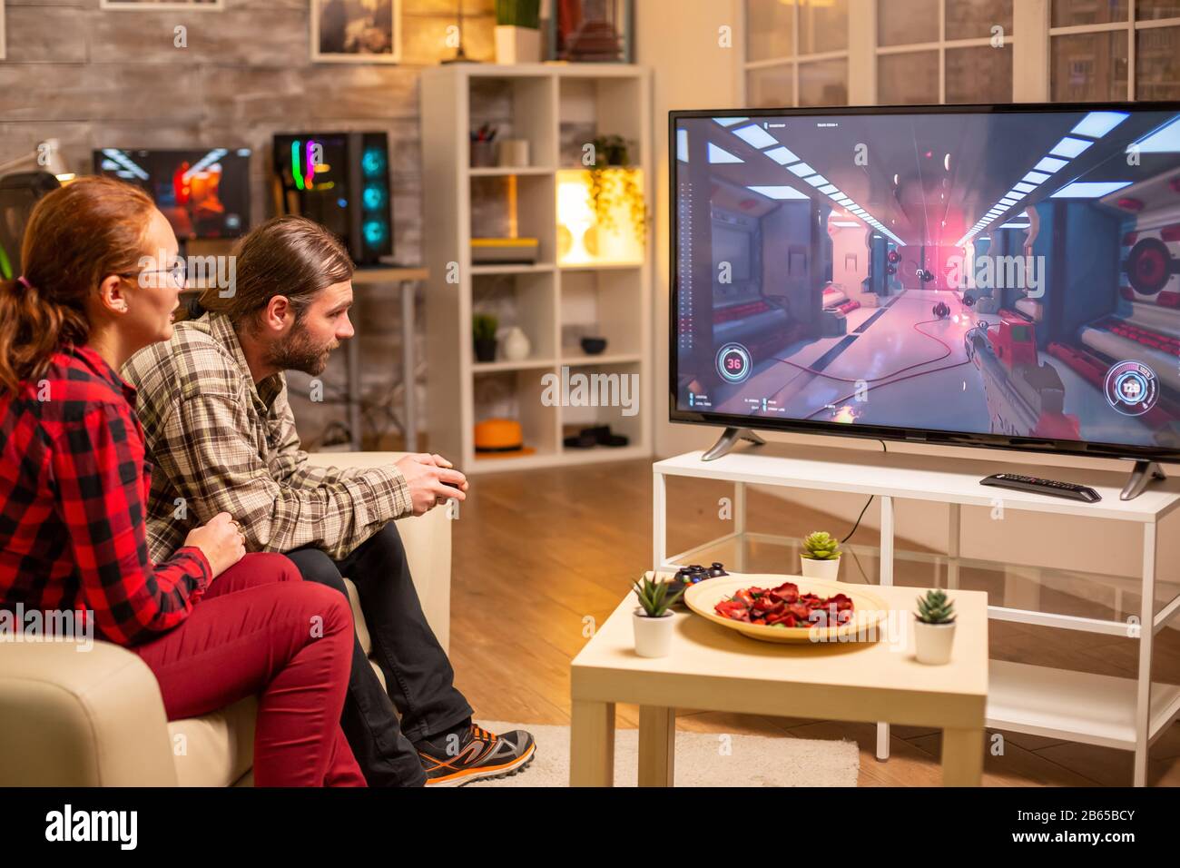 Couple playing video games on big screen TV in the living room late at ...
