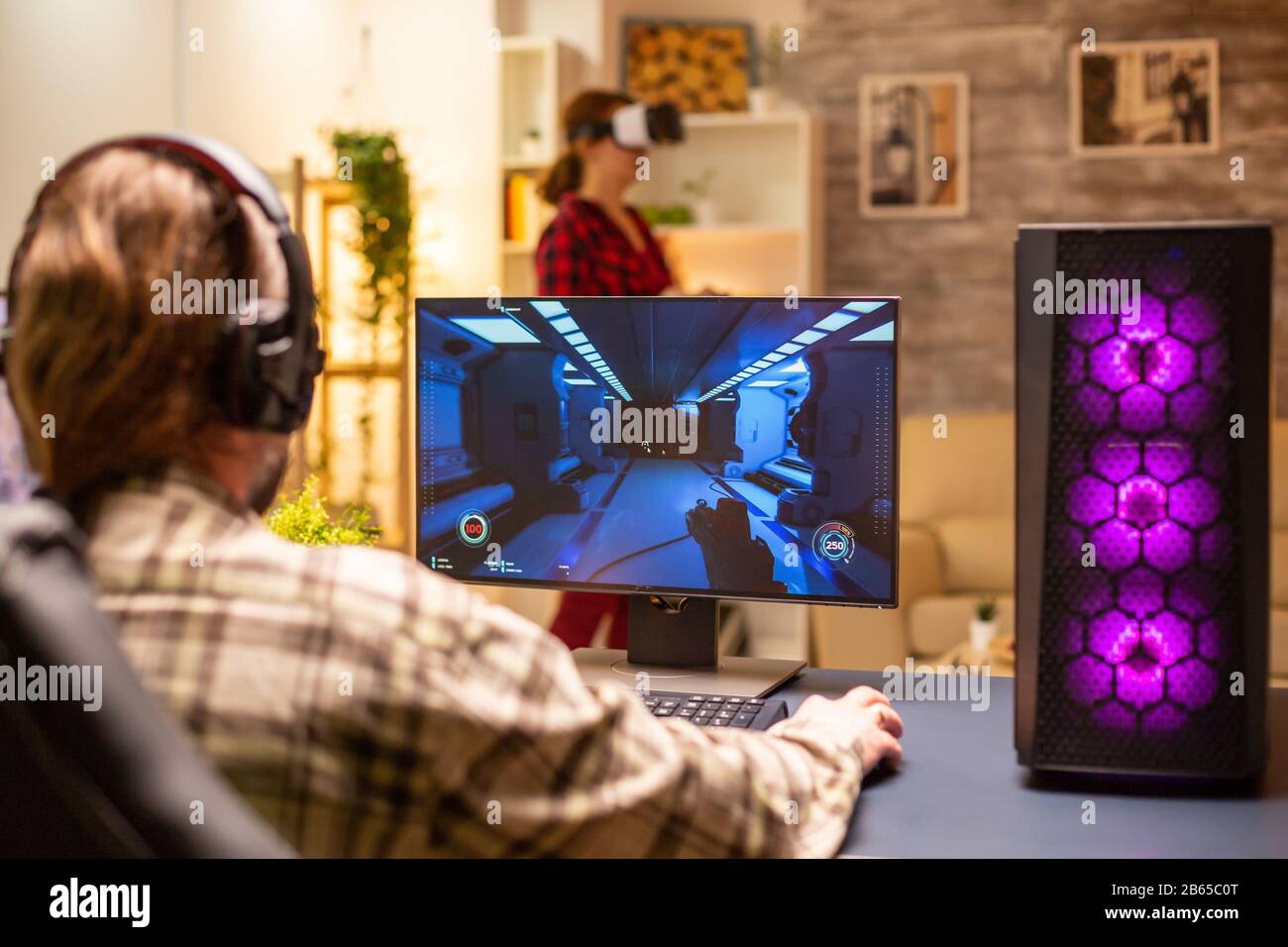 Back view of professional video gamer playing on powerful PC late at ...