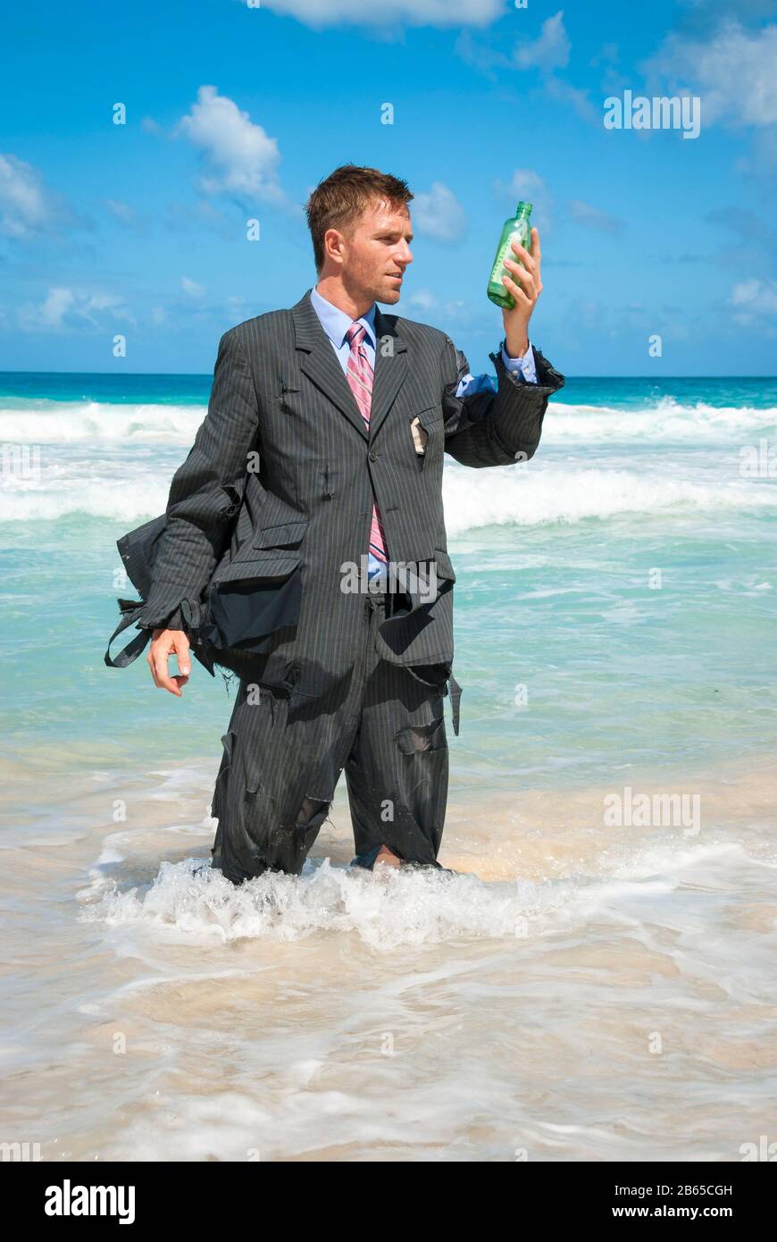 Castaway businessman standing on a tropical beach trying to read a ...