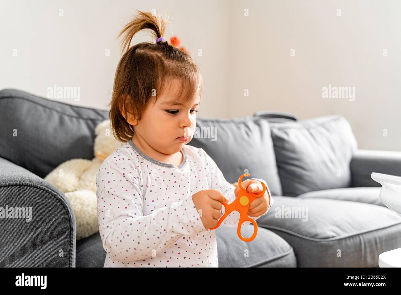 Toddler girl playing with plastic toy scissors at home Stock Photo - Alamy