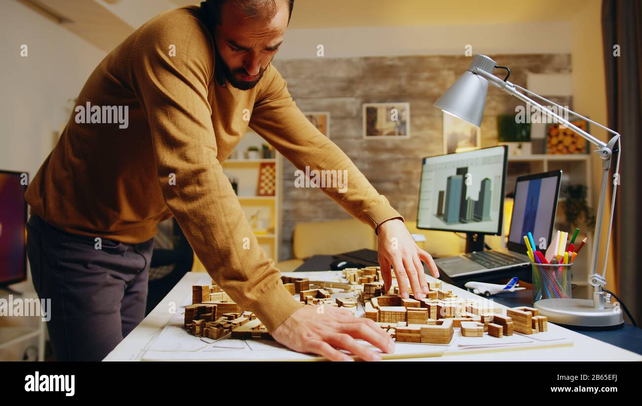 Successful architect talking on the phone while building a city model ...