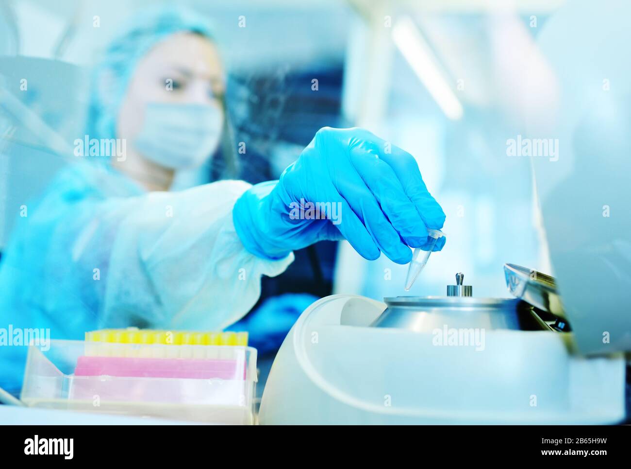 female scientist in a protective medical mask and rubber gloves makes ...