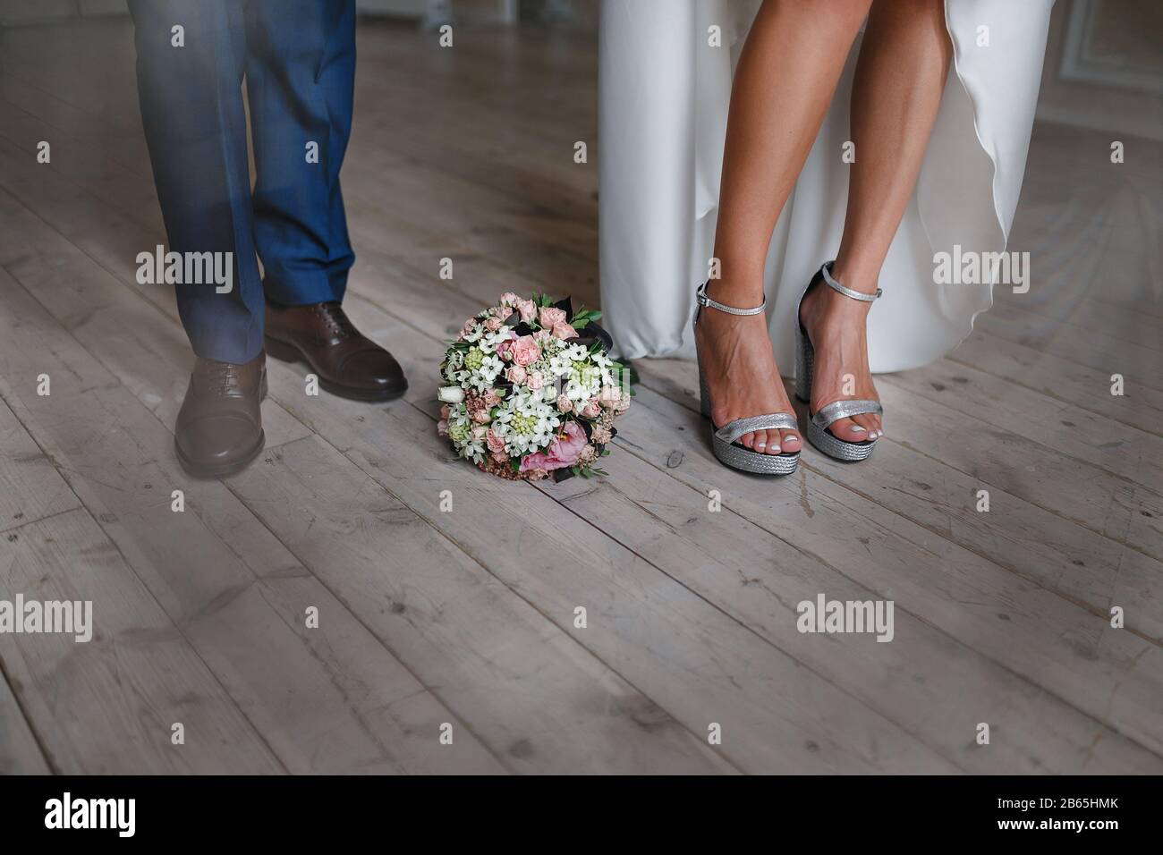 feet of bride and groom in wedding shoes on the floor with bouquet ...