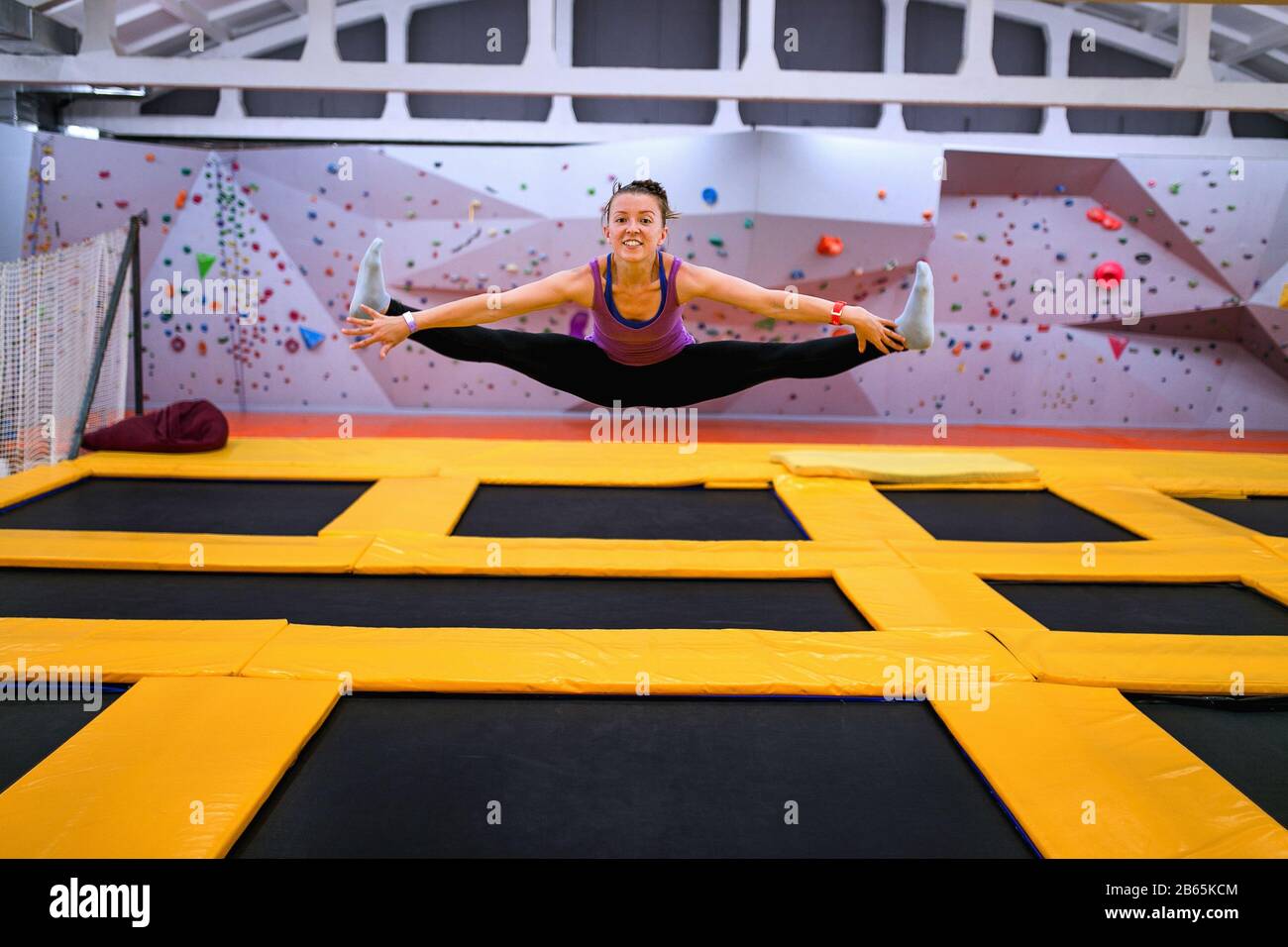 Young sportsman jumping on a trampoline and doing split indoors Stock ...