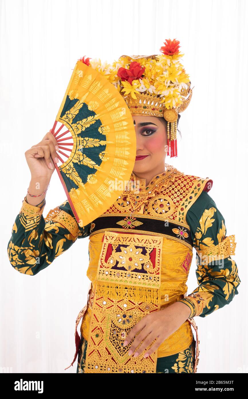 Dancers performing traditional Balinese dance holding a fan and ...