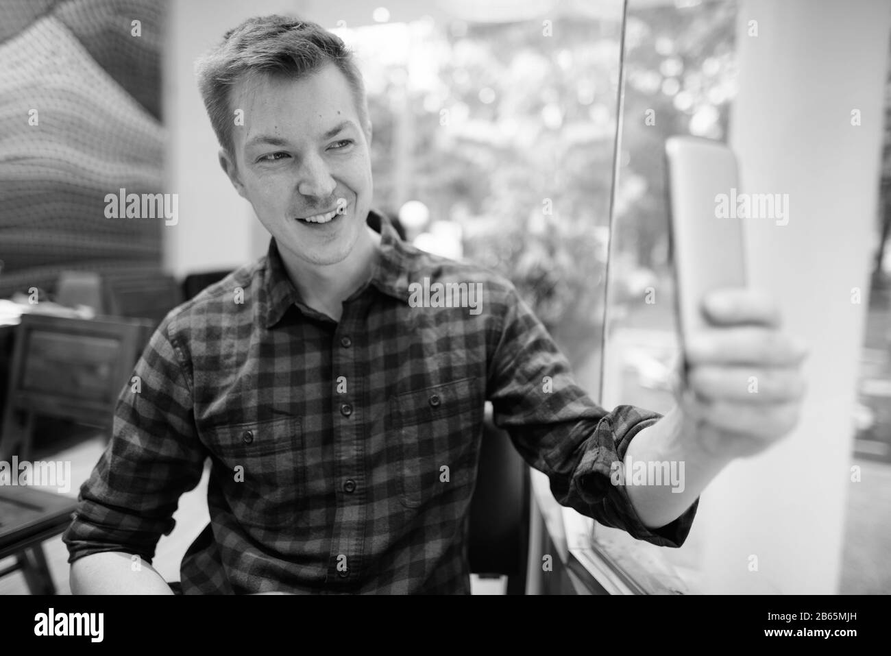 Happy young handsome tourist man taking selfie by the window Stock ...