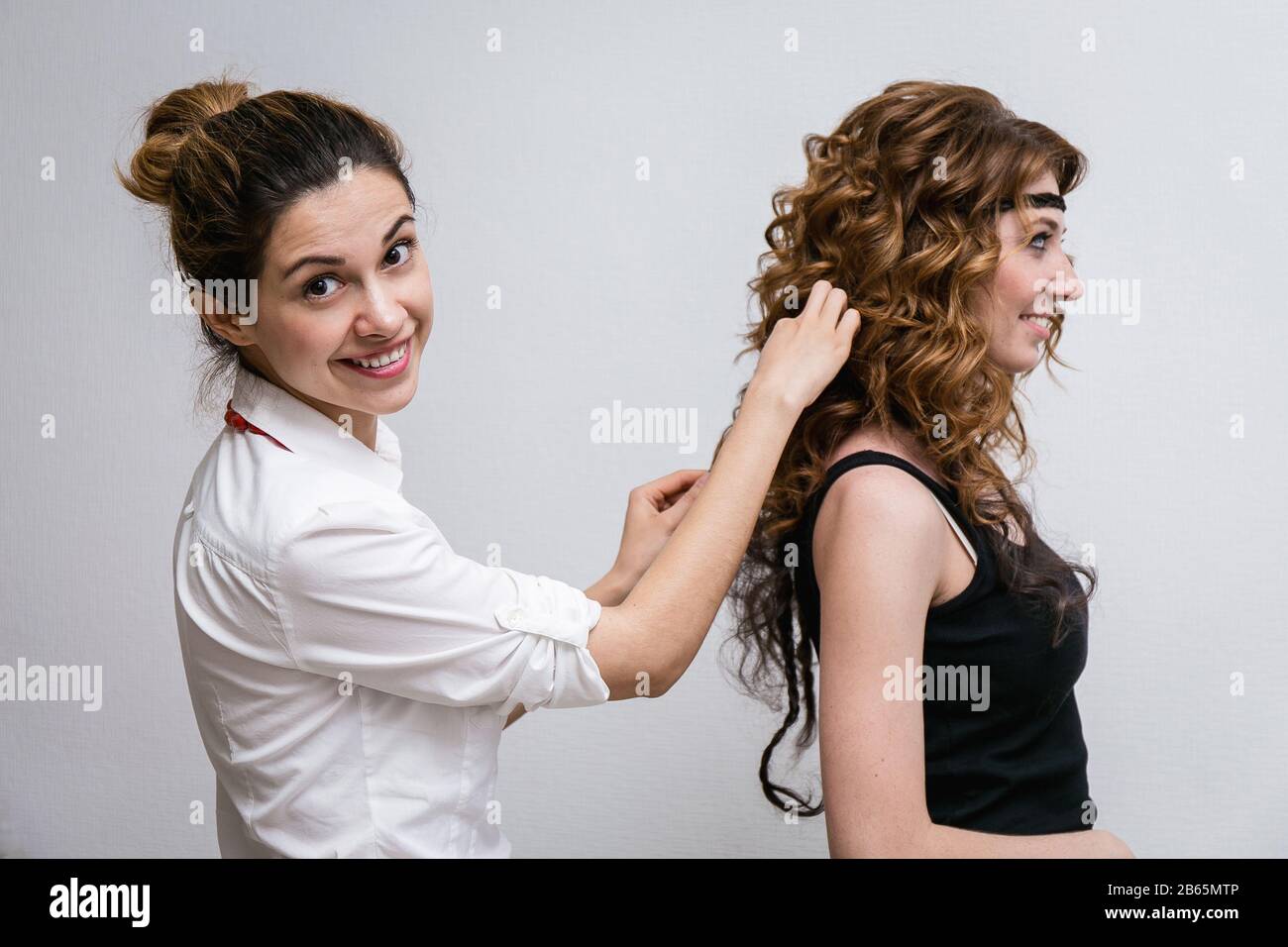 Creative woman hairdresser doing hairstyle to her client at hair salon ...