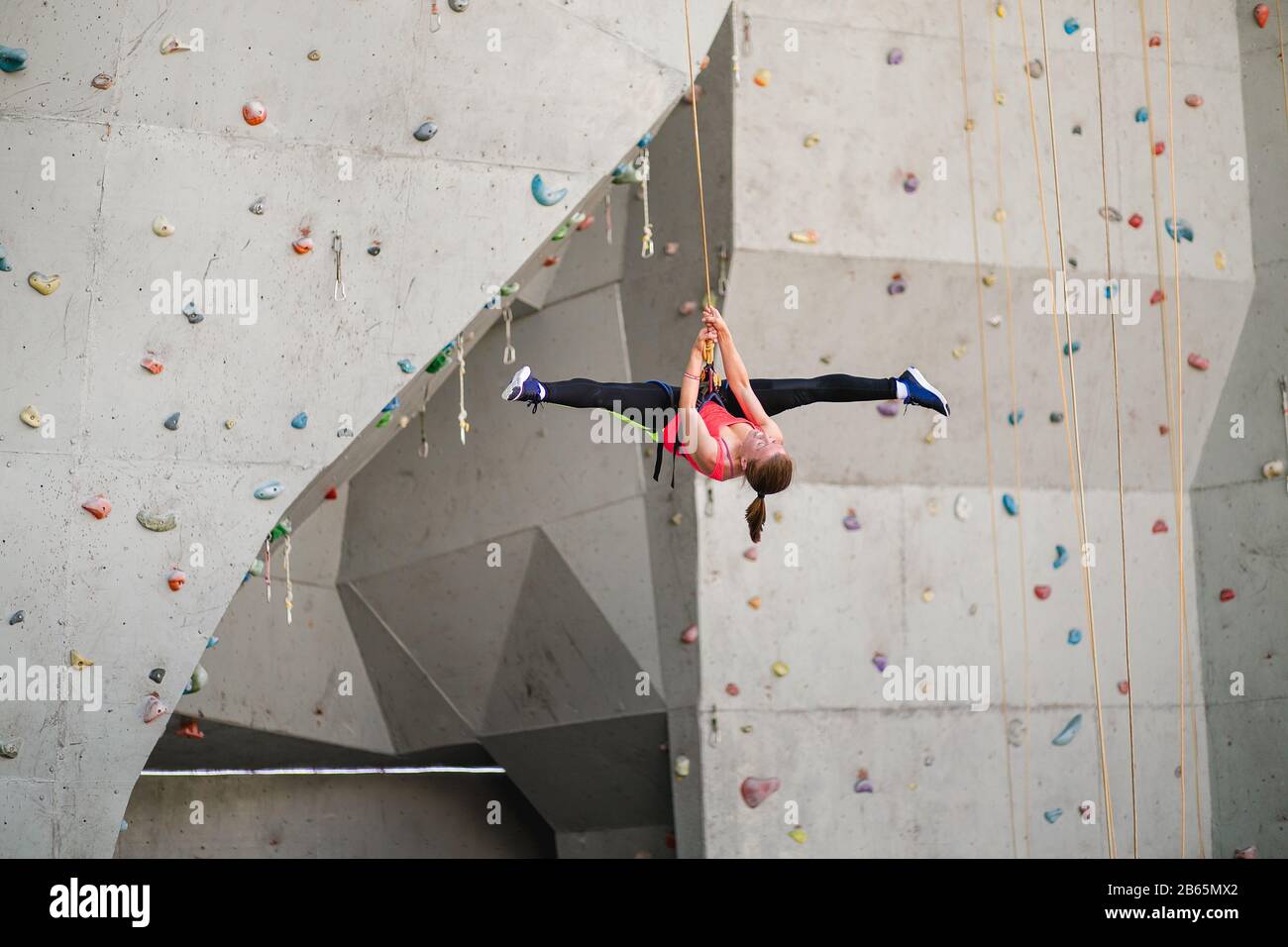 Active happy woman hanging on trope in the artificial climbing wall ...
