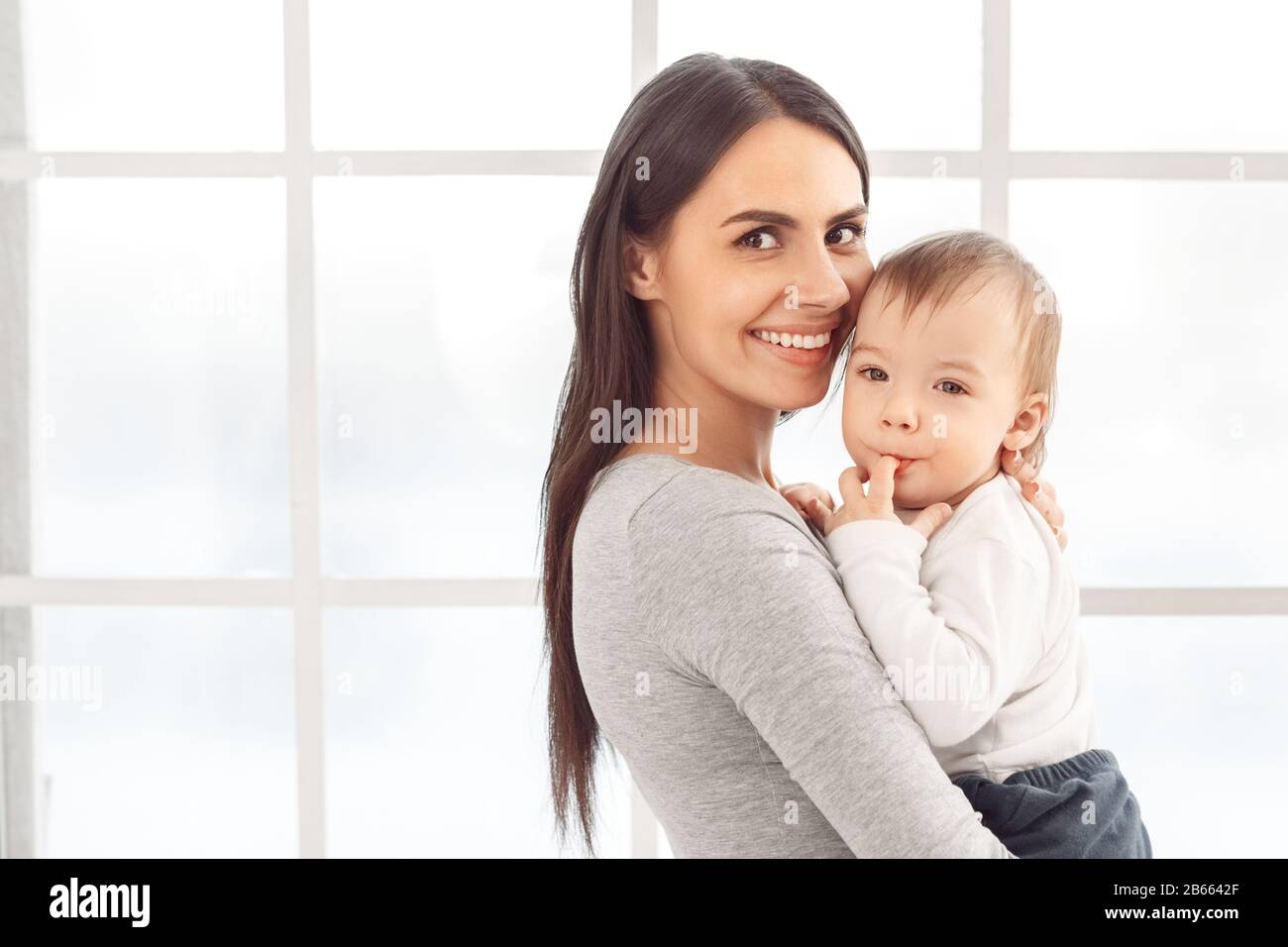 Motherhood. Mother standing holding son at home smiling happy Stock ...