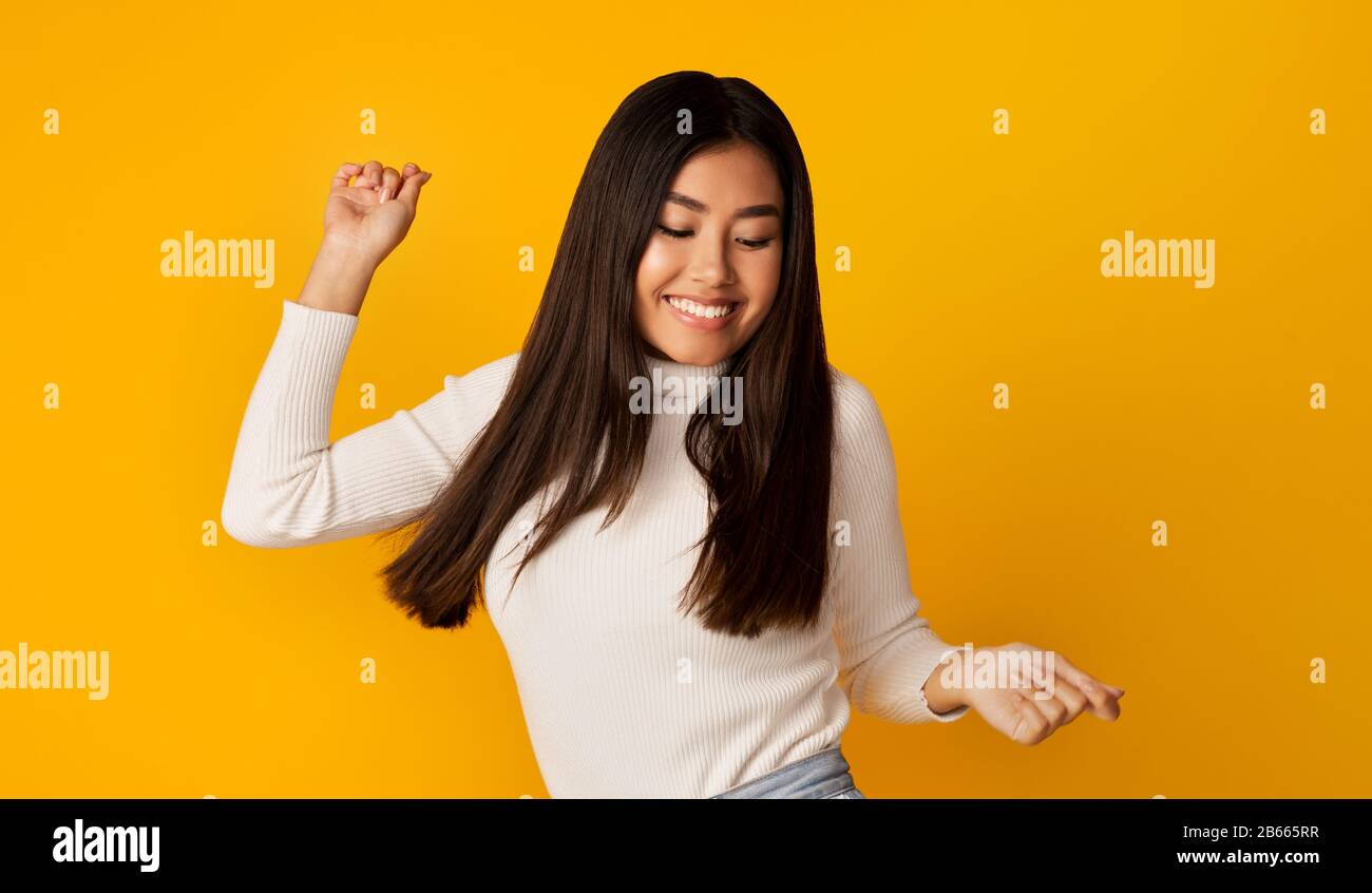 Happy Asian Girl Dancing Over Yellow Background, Studio Shot Stock ...