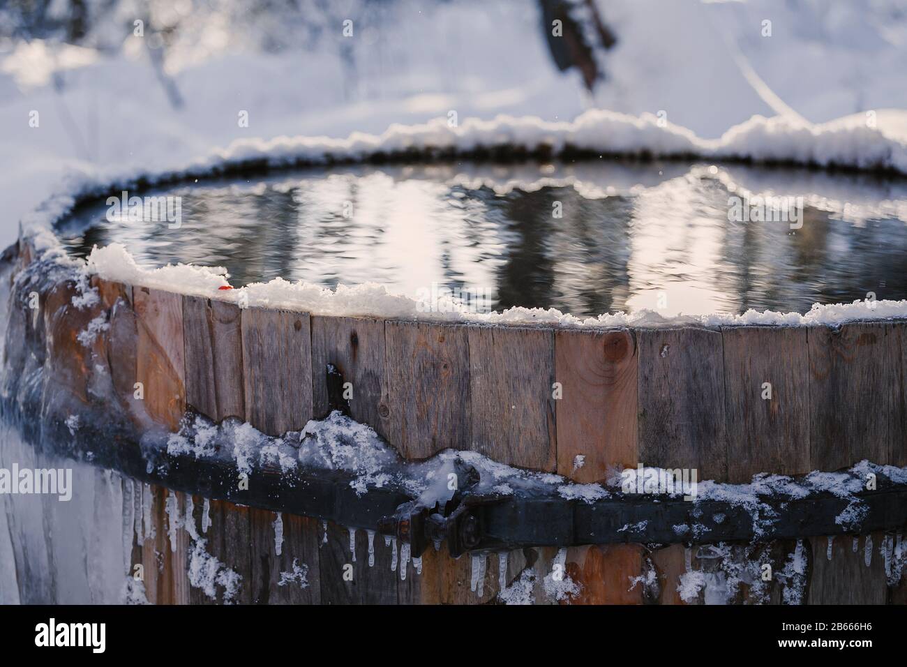 Big barrel with clean cold water outdoors in forest covered with snow ...