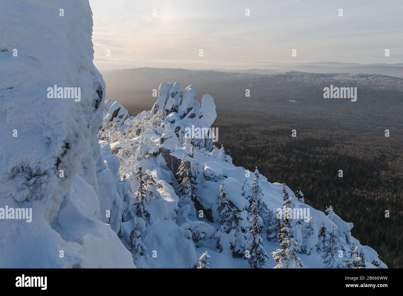 Rocky peak of basalt pillars covered by snow, winter forest in the ...