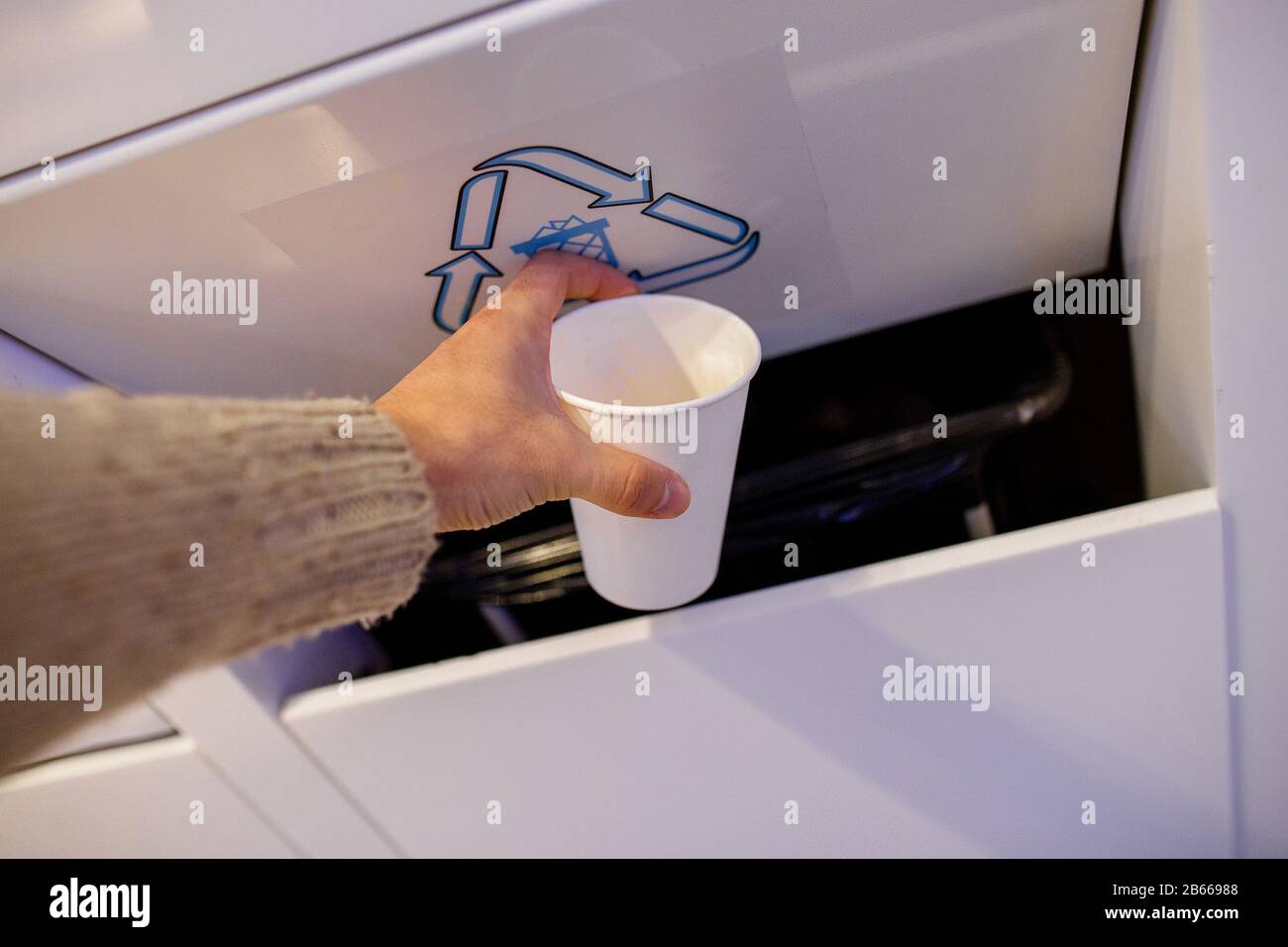 Closeup hand throwing empty paper disposable coffee cup in recycling ...
