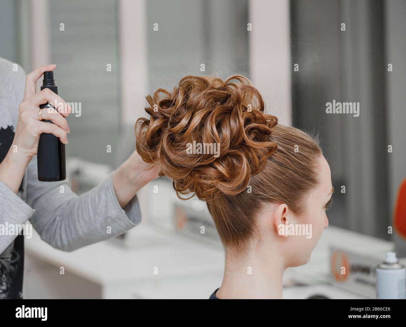 Closeup of hairdresser hands using hairspray styling on woman's healthy ...