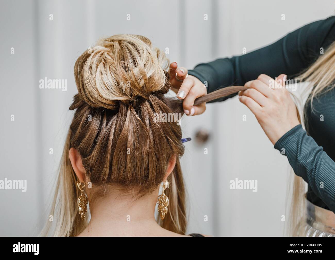 Hairdresser makes complex and beautiful hairstyle upper bun. Suitable ...