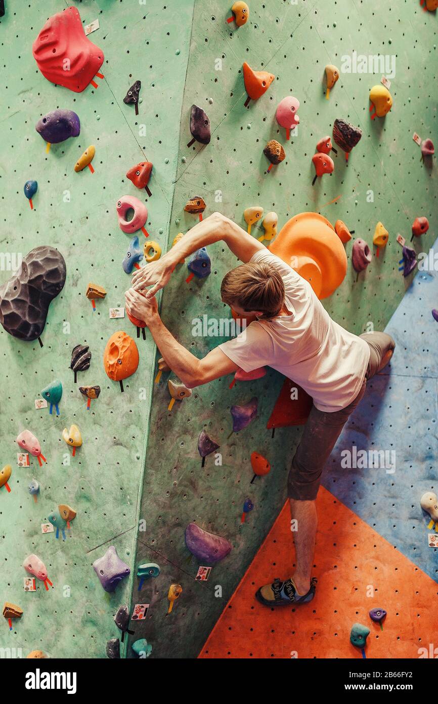 Young man professional climber exercising at indoor bouldering ...