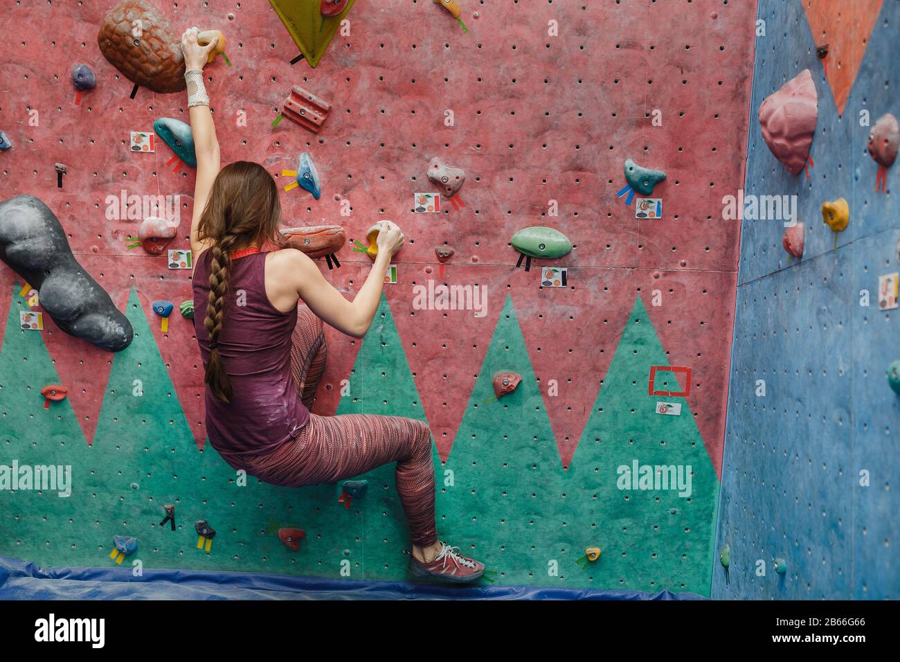 Young fitness woman doing professional bouldering in climbing gym ...