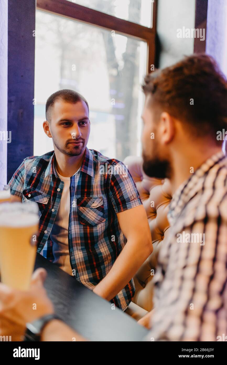 Two cheerful young men drinking beer in bar Stock Photo - Alamy
