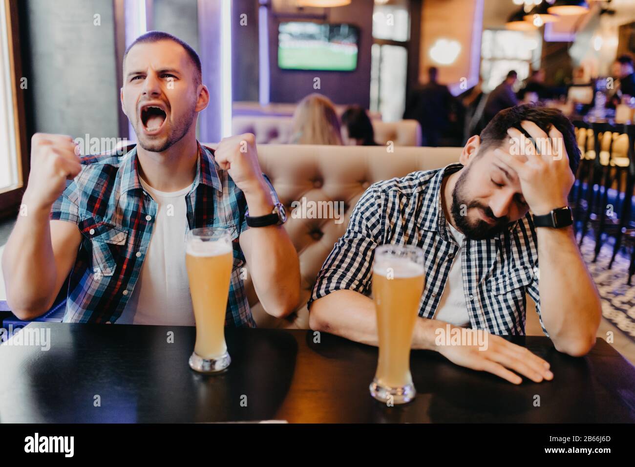 Two friends fans of different team with lose and win emotions while ...