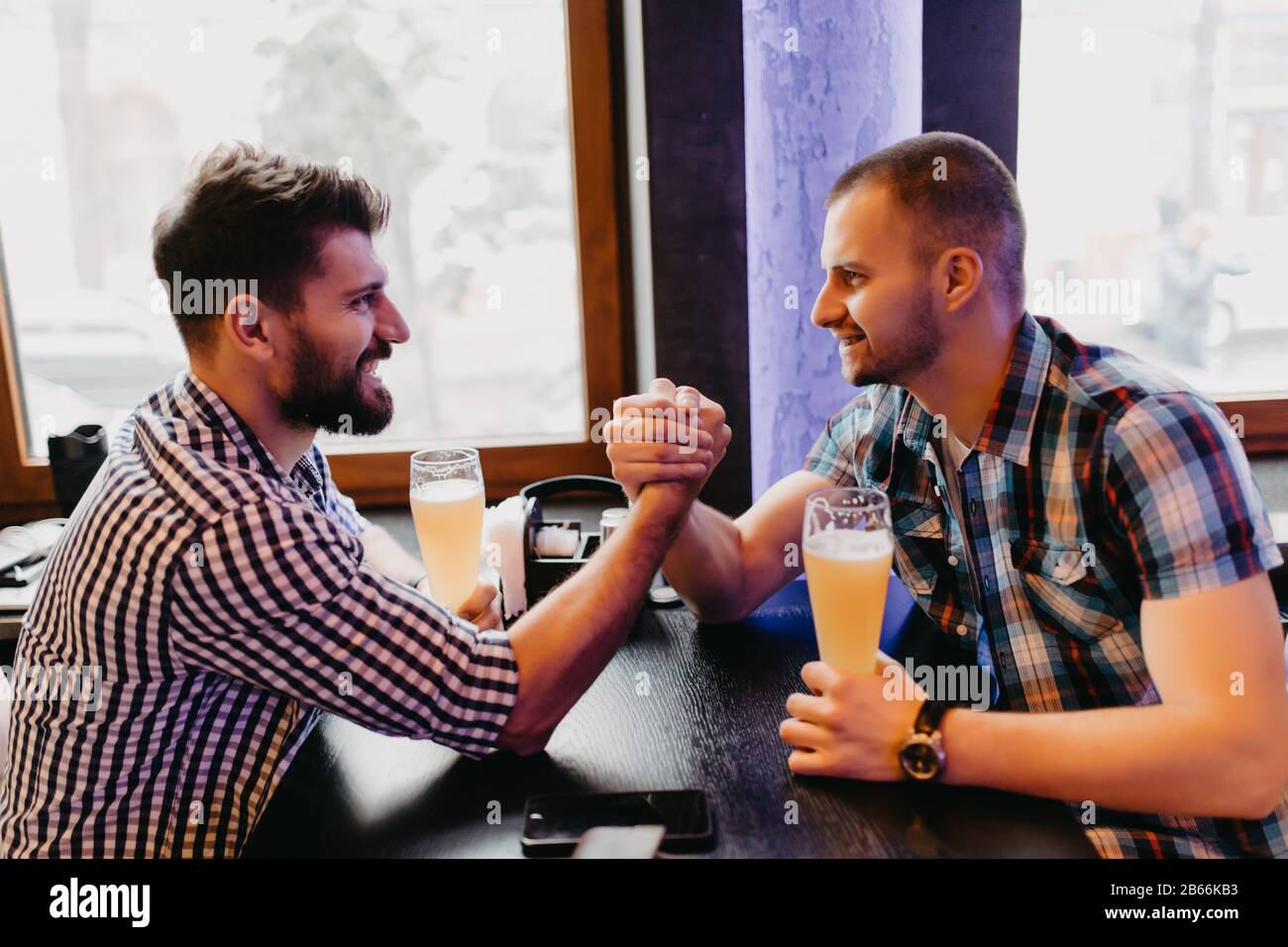 happy male friends drinking beer and have hands fight at pub Stock ...