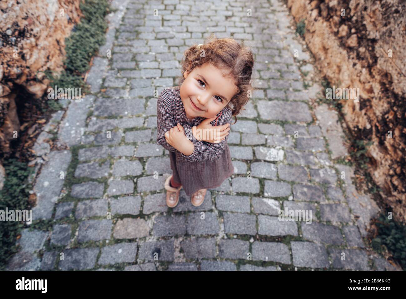 Pretty baby girl hold arms closed with a shy gesture and walk on a ...