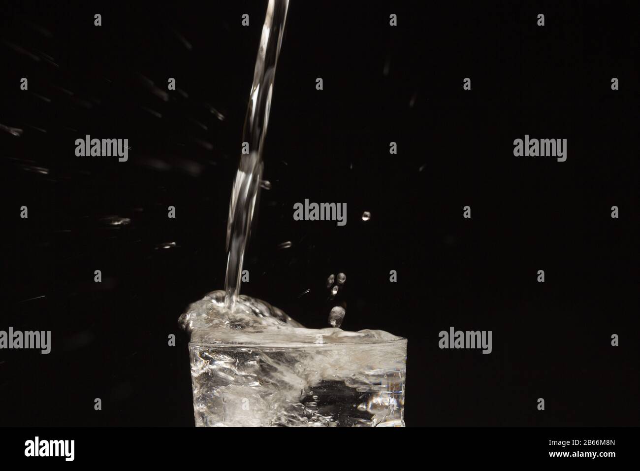 Water jet falling into a glass and generating a splash of water ...