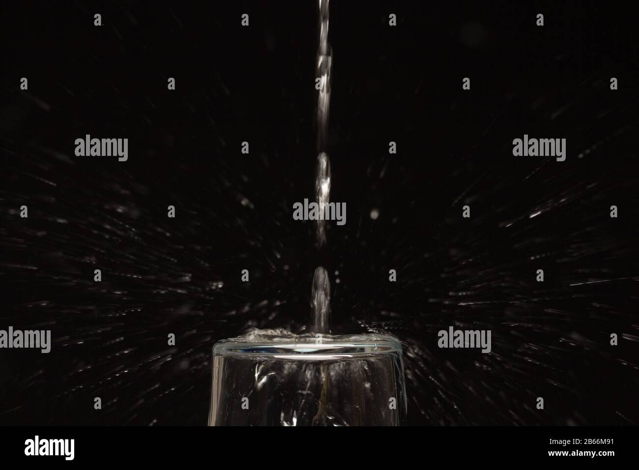 Water jet falling into a glass and generating a splash of water ...